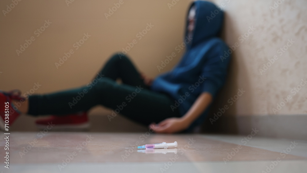 Addict sits in dark corner next to syringe with needle. Drug abuse and ...