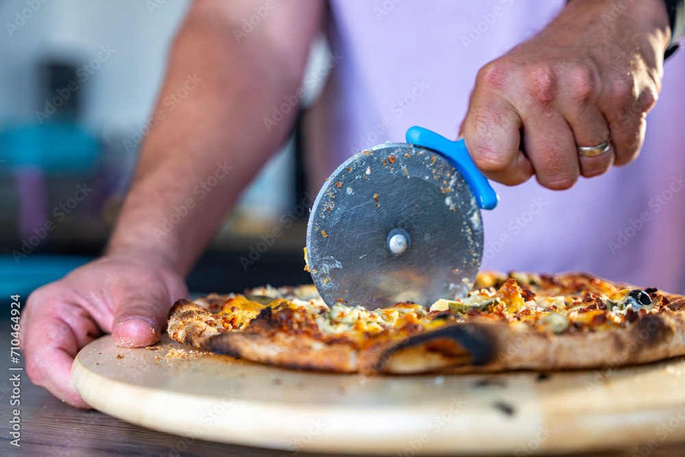main d'homme en train de découper une pizza avec une roulette Stock Photo | Adobe Stock