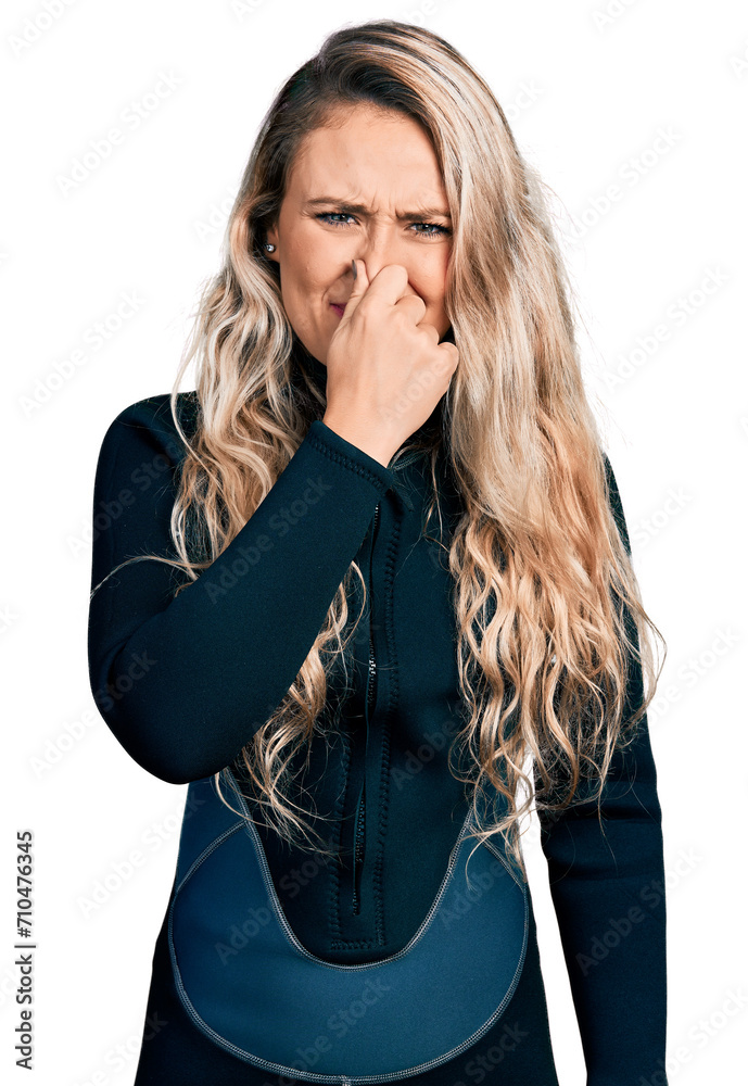 Young blonde woman wearing diver neoprene uniform smelling something ...