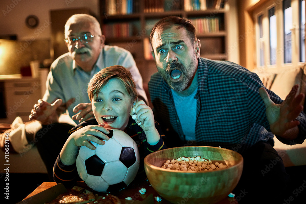 Multigenerational group of males watching a football soccer game on the ...