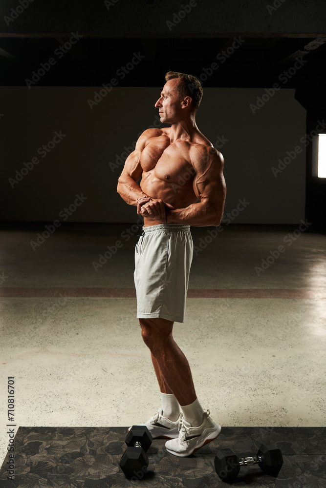 Like a modern Hercules, a young, muscular man flexes with bronze-like ...