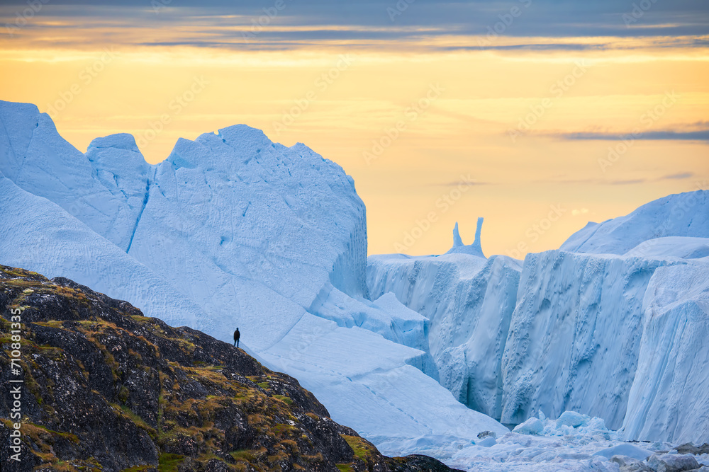 Tourist man explorer watching a large iceberg melting in the arctic sea ...