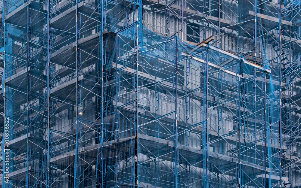 building under construction covered in blue mesh tarp protective wrap ...