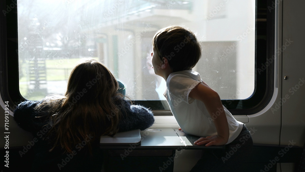 Kids sitting by train window, little brother covering face and eyes ...