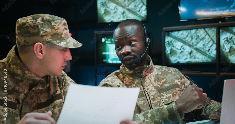Multiethnic male co-workers sitting in control room and studying ...