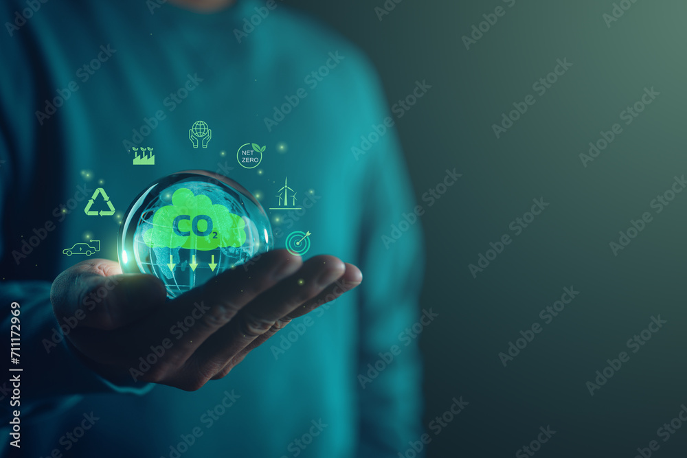 Hand holding globe with CO2 reducing icon with virtual world for decrease carbon dioxide ...