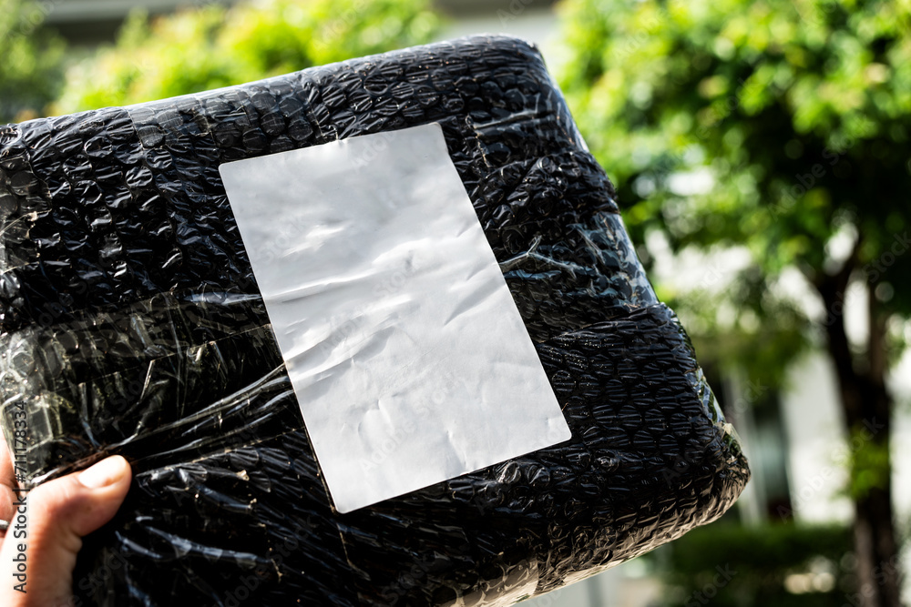 Man holding parcel with black bubble wrapped and empty label. Packaging ...