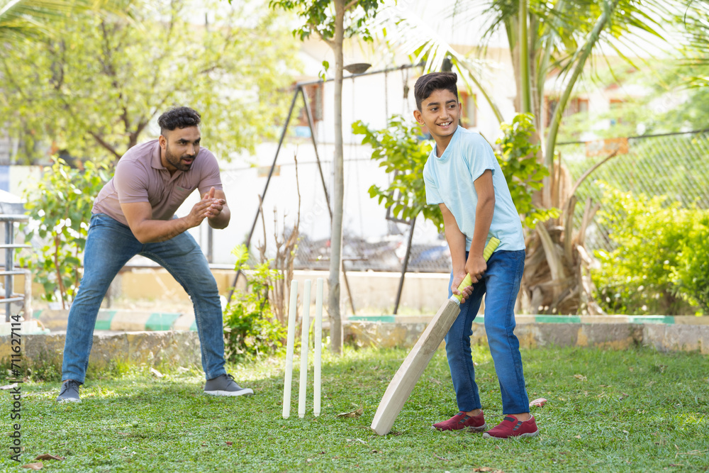 Cheerful indian father encouraging son from behind while playing ...