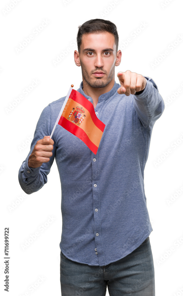 Handsome young man holding a flag of Spain pointing with finger to the ...