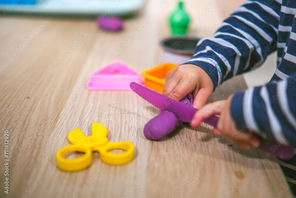 Manos de niña de 2 años jugando con plastilina casera y moldes. Jugar ...
