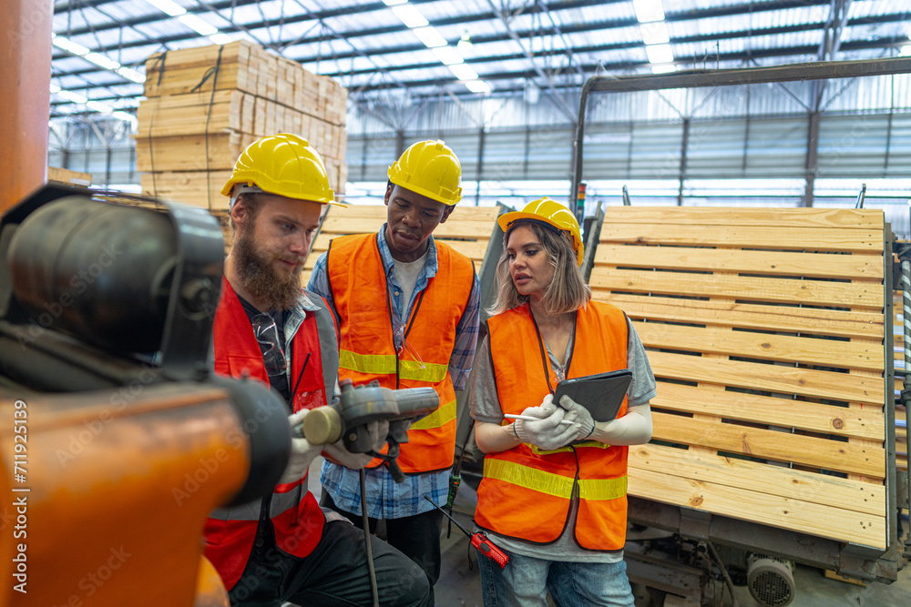team Engineers standing by robotic arm and operating machine in factory ...