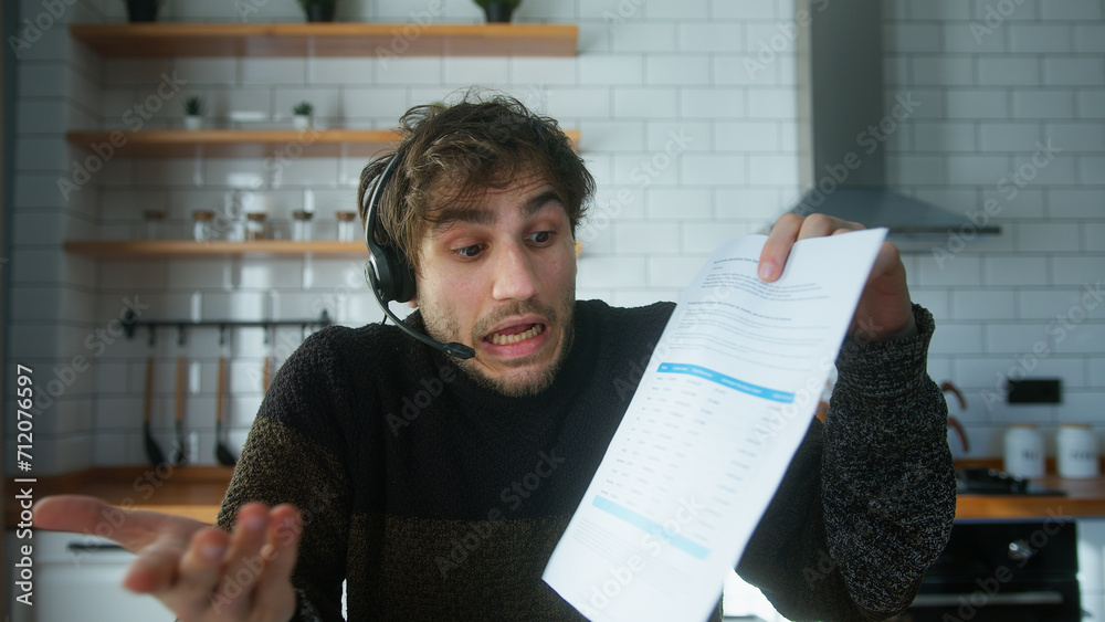 Foto de Young man with wireless headset sitting in modern kitchen at ...