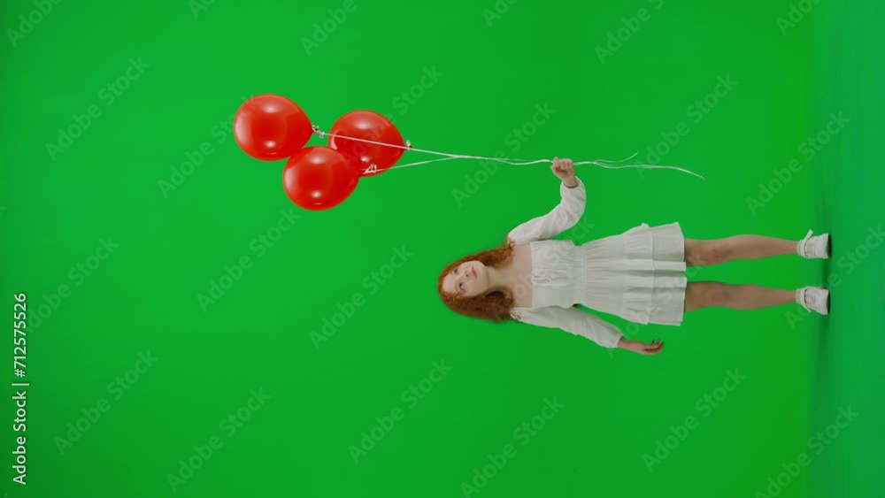 Little girl in white dress with red helium balloons on chroma key green ...