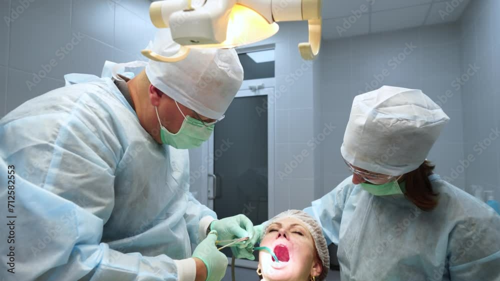 Oral surgeon, nurse doing medical operation on root canals in operating ...