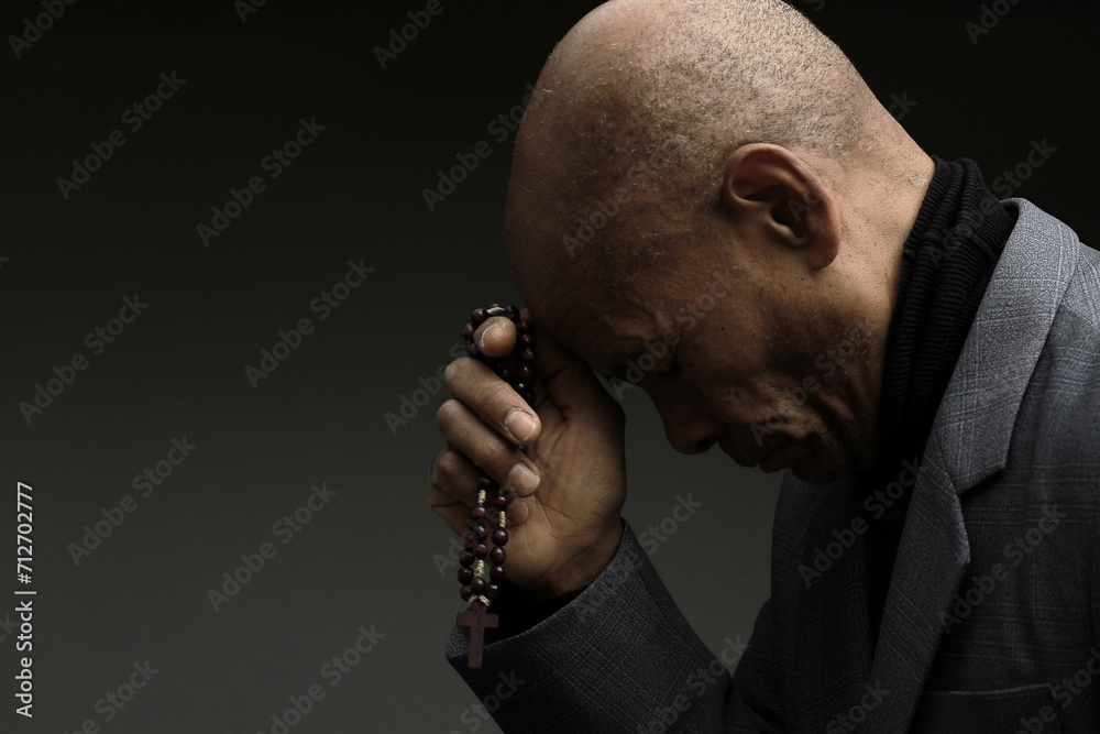 praying to god Caribbean man praying with black background with people ...