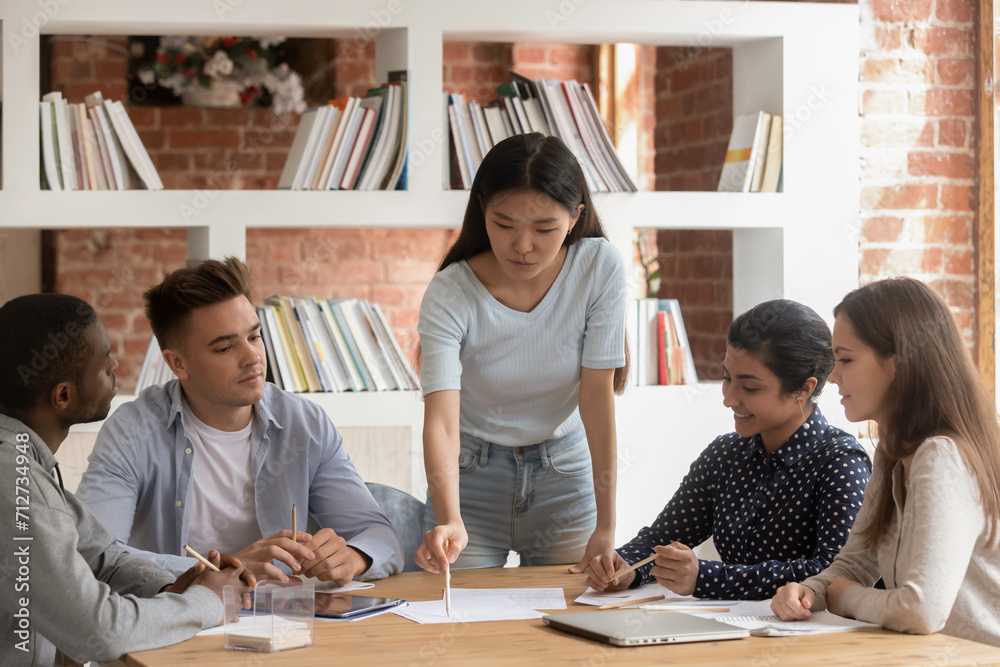 Motivated Asian female group leader stand explaining work on project ...