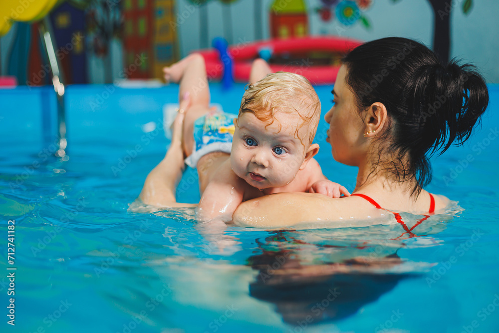 Teaching a newborn boy to swim in a pool with a coach. Baby swimming ...