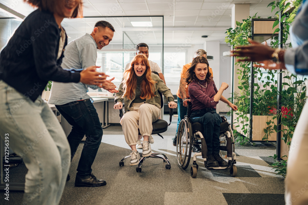 Ginger woman and a woman with disability having fun in an office chair ...
