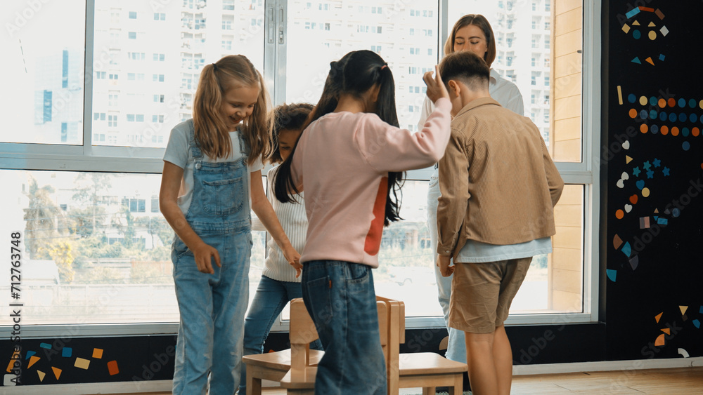 Diverse children playing musical chairs games while young smart ...