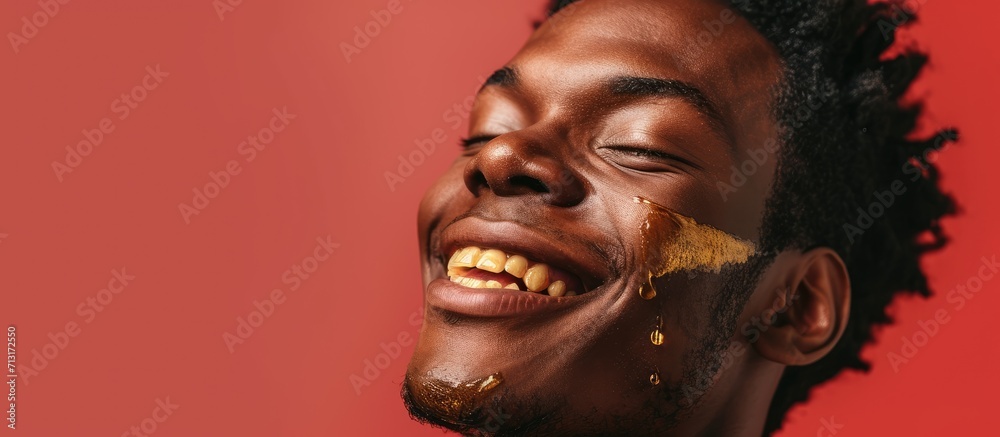 Young black man smiling while applying beauty oil to his melanated face ...