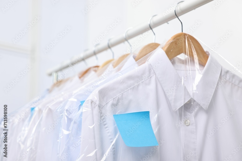 Dry-cleaning service. Many different clothes in plastic bags hanging on ...
