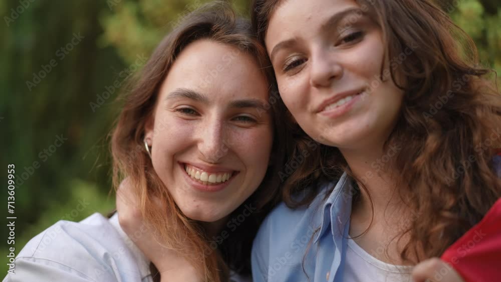Close-up. Two teenage girls stand hugging each other in a city park ...