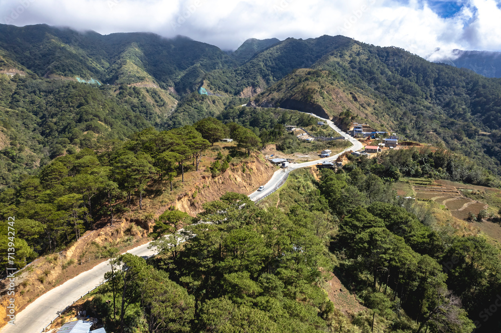 Aerial view of a winding road cutting through a lush mountain landscape ...