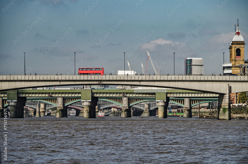 Red London Bus on bridge over River Thames with maritime traffic ...