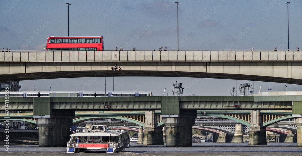 Red London Bus on bridge over River Thames with maritime traffic ...