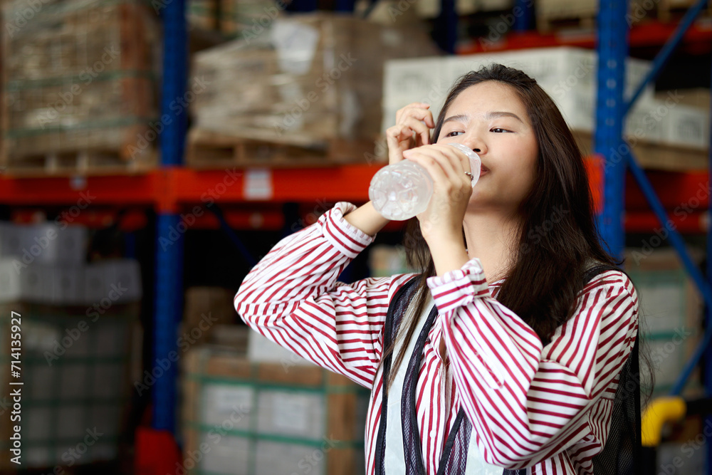 Tired young Asian woman wearing safety vest and helmet feeling hot and ...