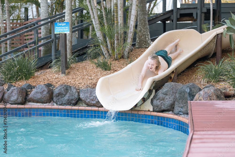 Boy enjoying water slide splash park at tropical Australian caravan ...