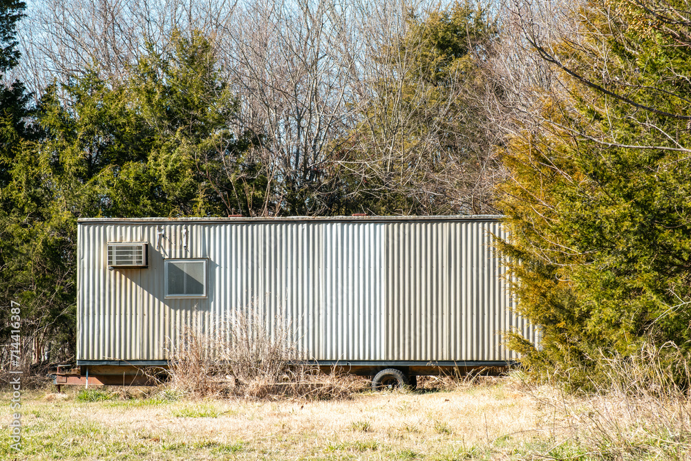 An old abandoned trailer in the woods with a a single windows and an AC ...