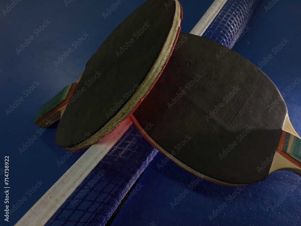 Two rackets for playing ping-pong, on a tennis table, are propped up on ...