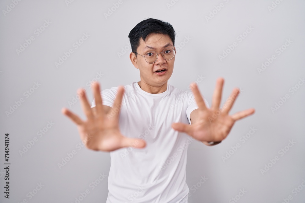 Young asian man standing over white background afraid and terrified ...