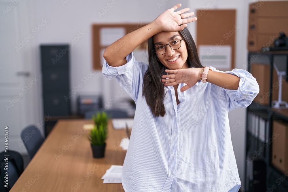 Young hispanic woman at the office smiling cheerful playing peek a boo ...