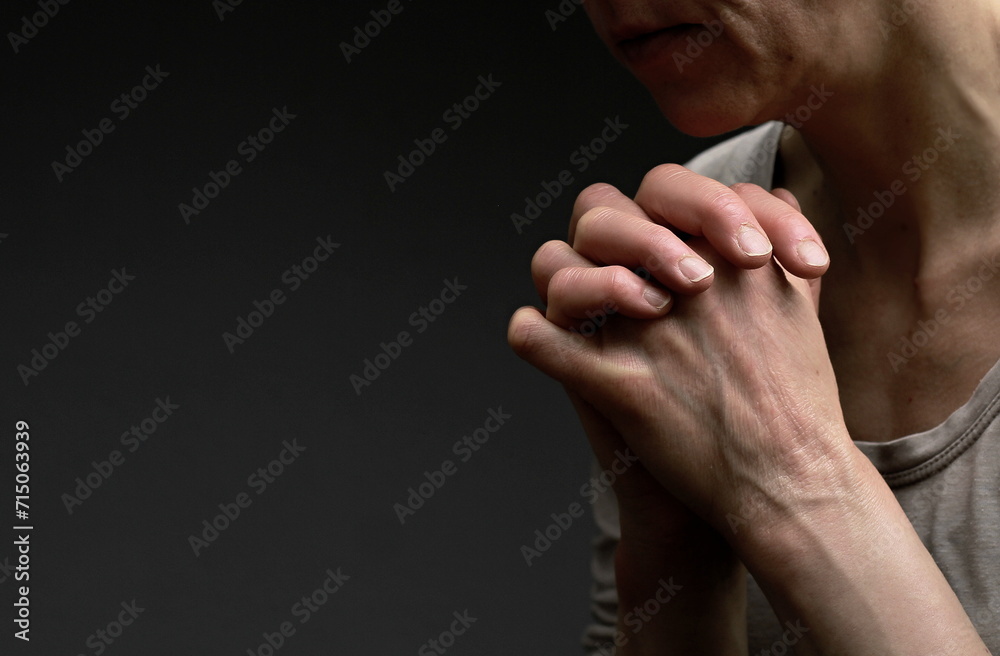 woman praying with hand over her face on black background with people ...