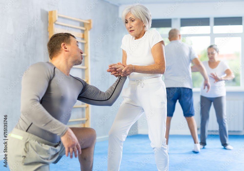 Senior woman train in pair with middle-aged coach to strike and reflect ...