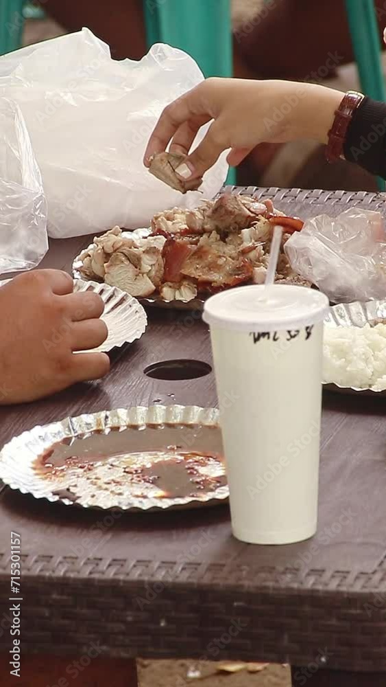Two people eating pork lechon with their hands, a famous Filipino local ...