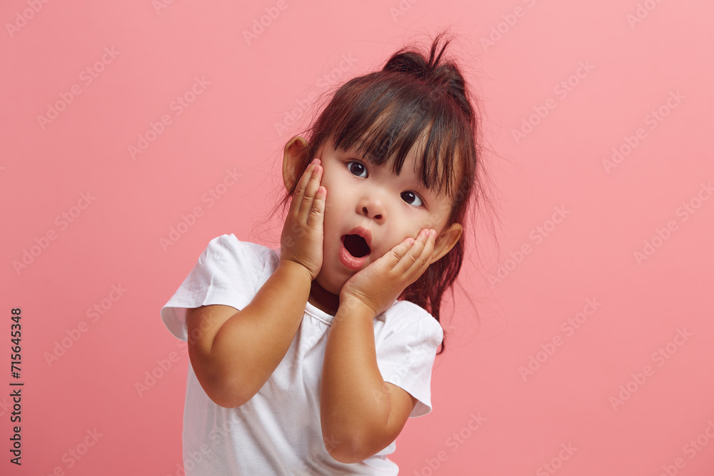 Amazed horrified little three years old girl keeps mouth opened, hands ...