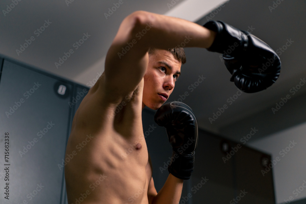 portrait of a young boy boxer in boxing gloves practicing his punches ...
