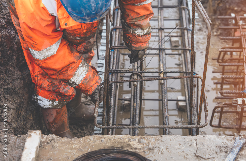 A worker uses steel tying wire to fasten steel rods to reinforcement ...
