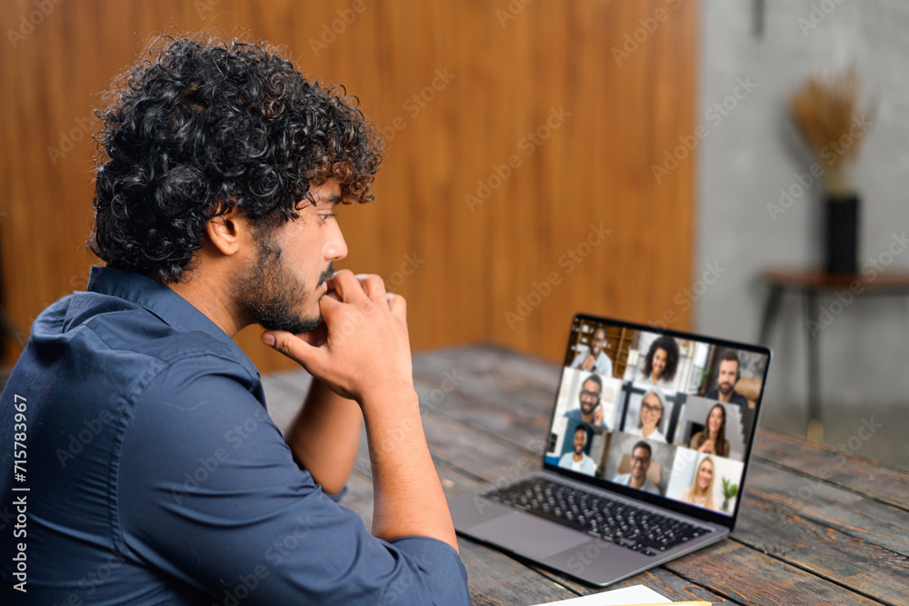 Indian man sits at a wooden table, engrossed in a serious discussion ...