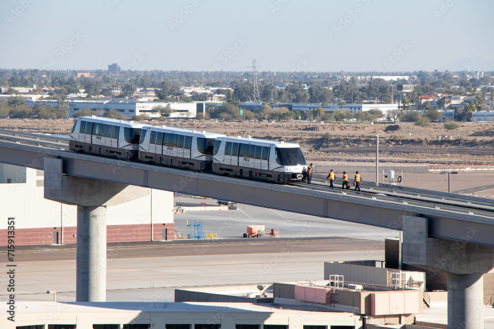 Rail workers walking in front of a PHX Sky Train at Phoenix Sky Harbor ...