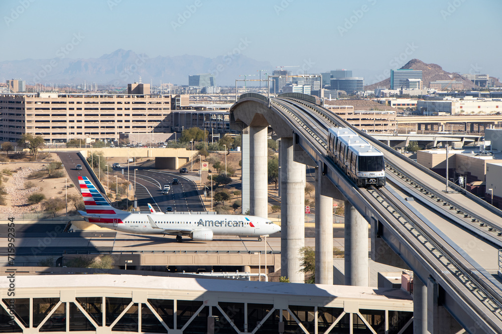 PHX Sky Train on rail bridge above an American Airlines Boeing 737 at ...