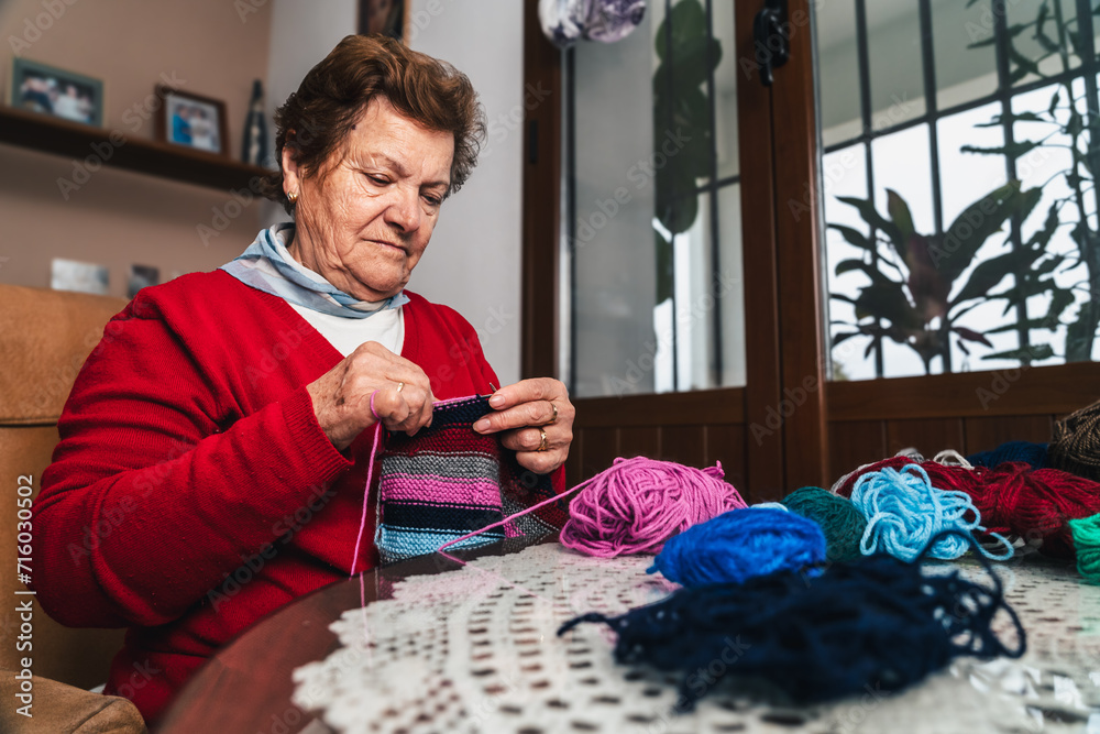 older woman weaving a piece of wool for clothing in an artisanal way ...