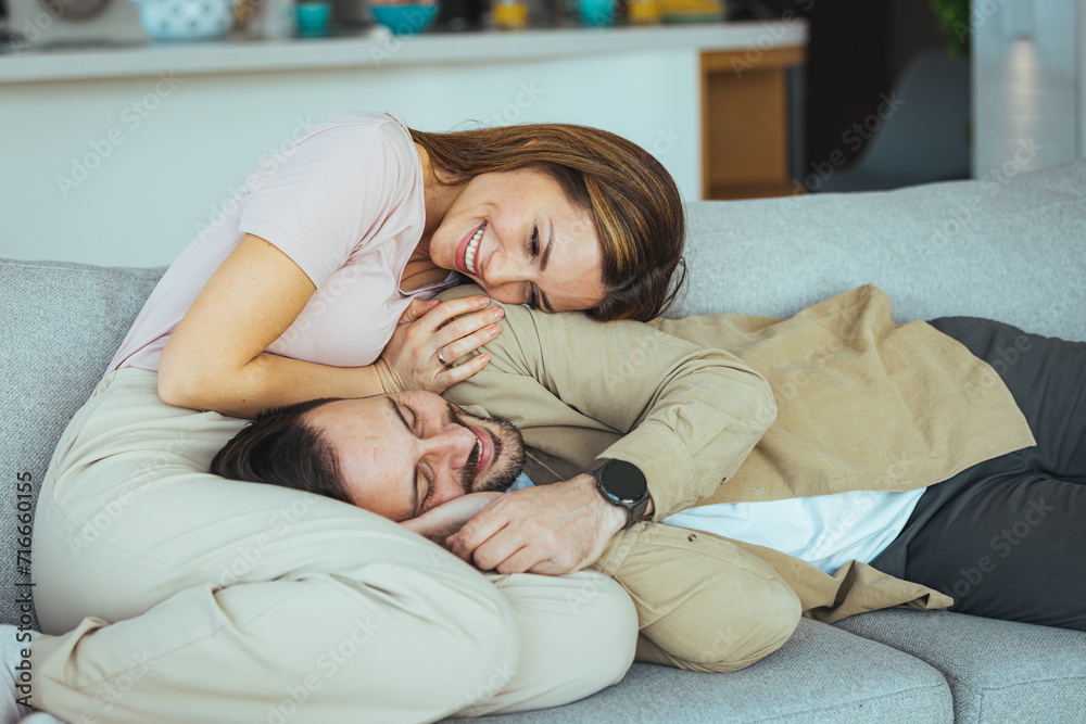 Mand and woman couple hugging each other lying on sofa at home. Couple ...