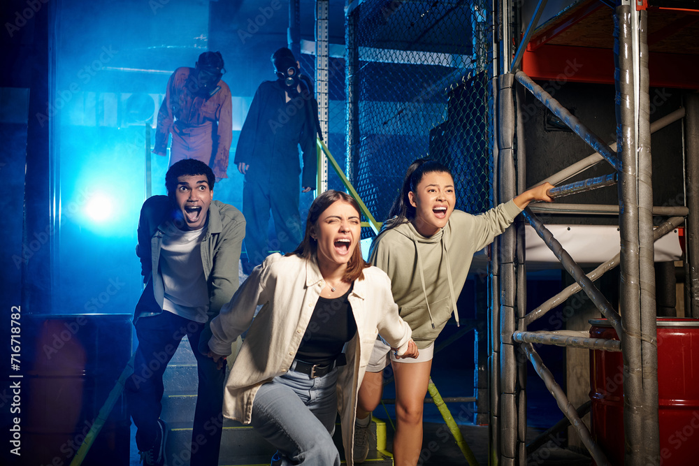 scared multicultural friends running from freaky people in gas masks ...