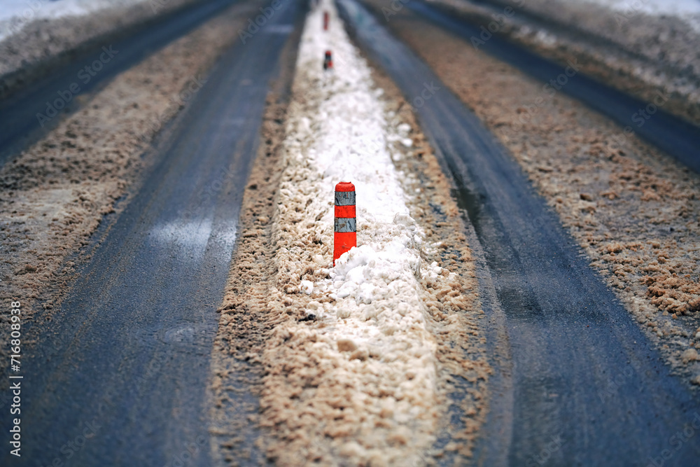 Foto de Asphalt roadway covered with slushy snow and orange plastic ...