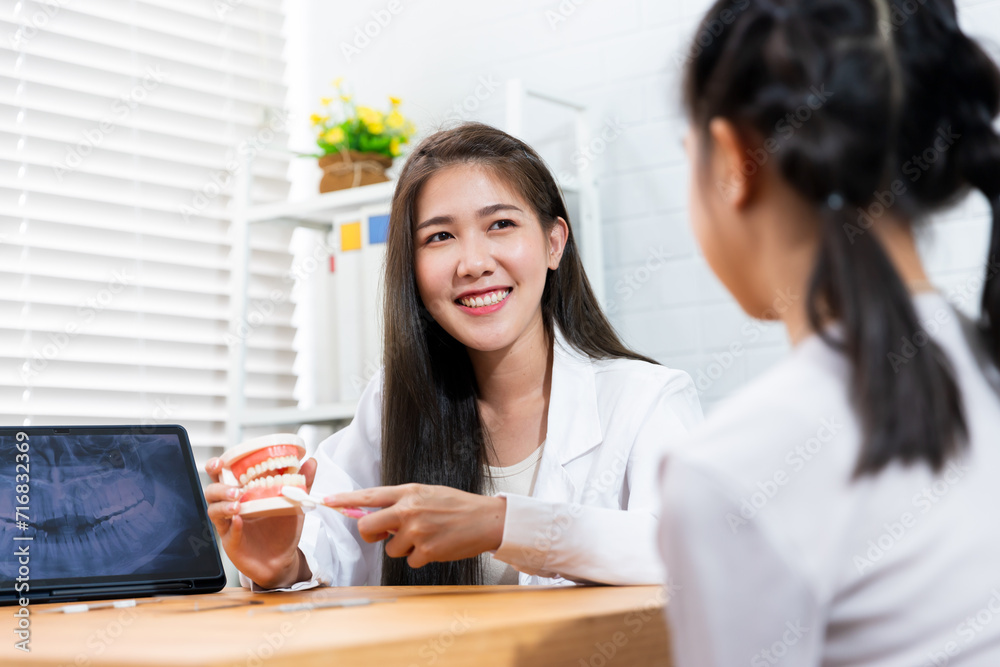 Asian female doctor dentist with young child patient examining ...