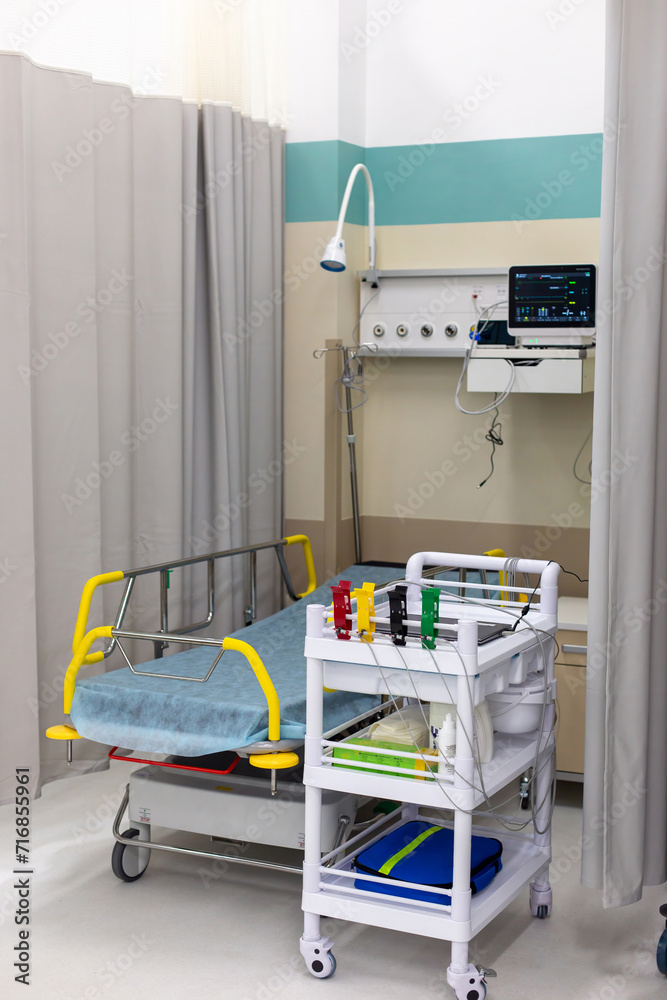 Hospital room setup with an empty patient bed, a medical trolley, and a ...